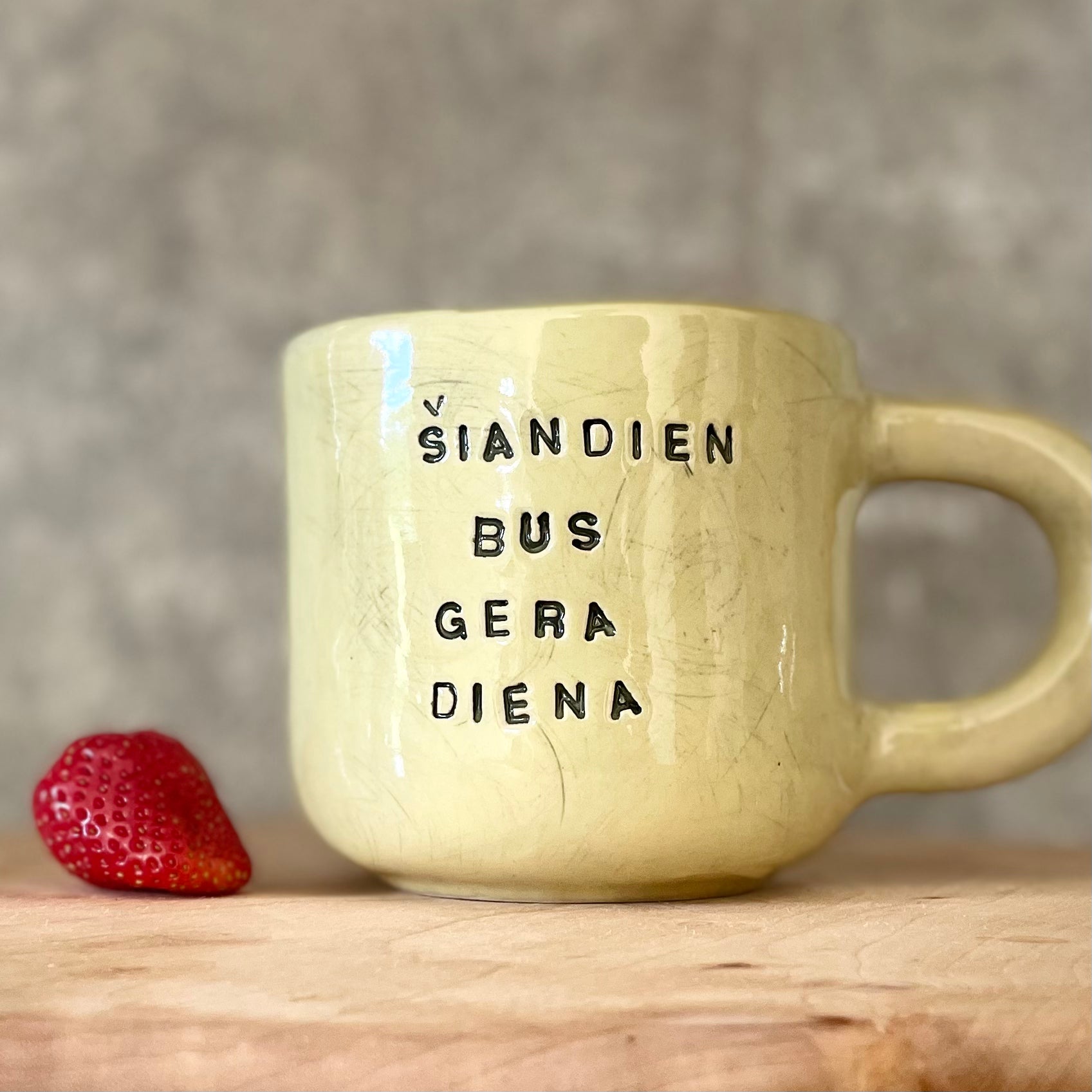 Large yellow mug with text in Lithuanian